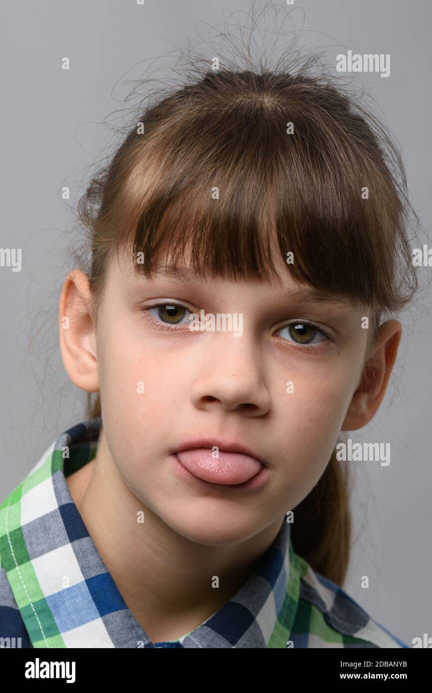 Portrait of a ten-year-old girl sticking out her tongue from resentment ...