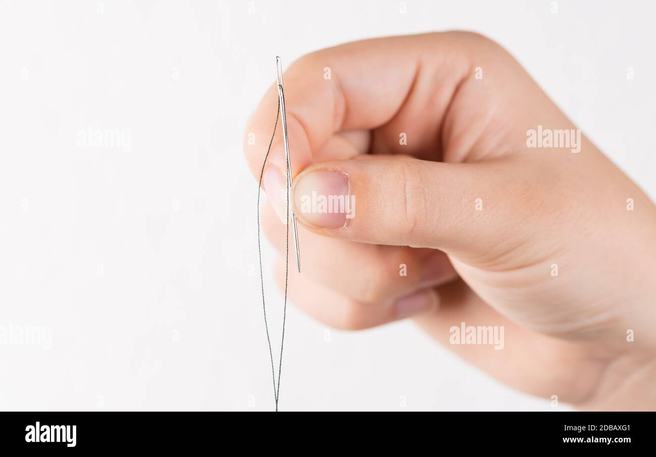 Detail of hand holding needle with thread on white background Stock ...