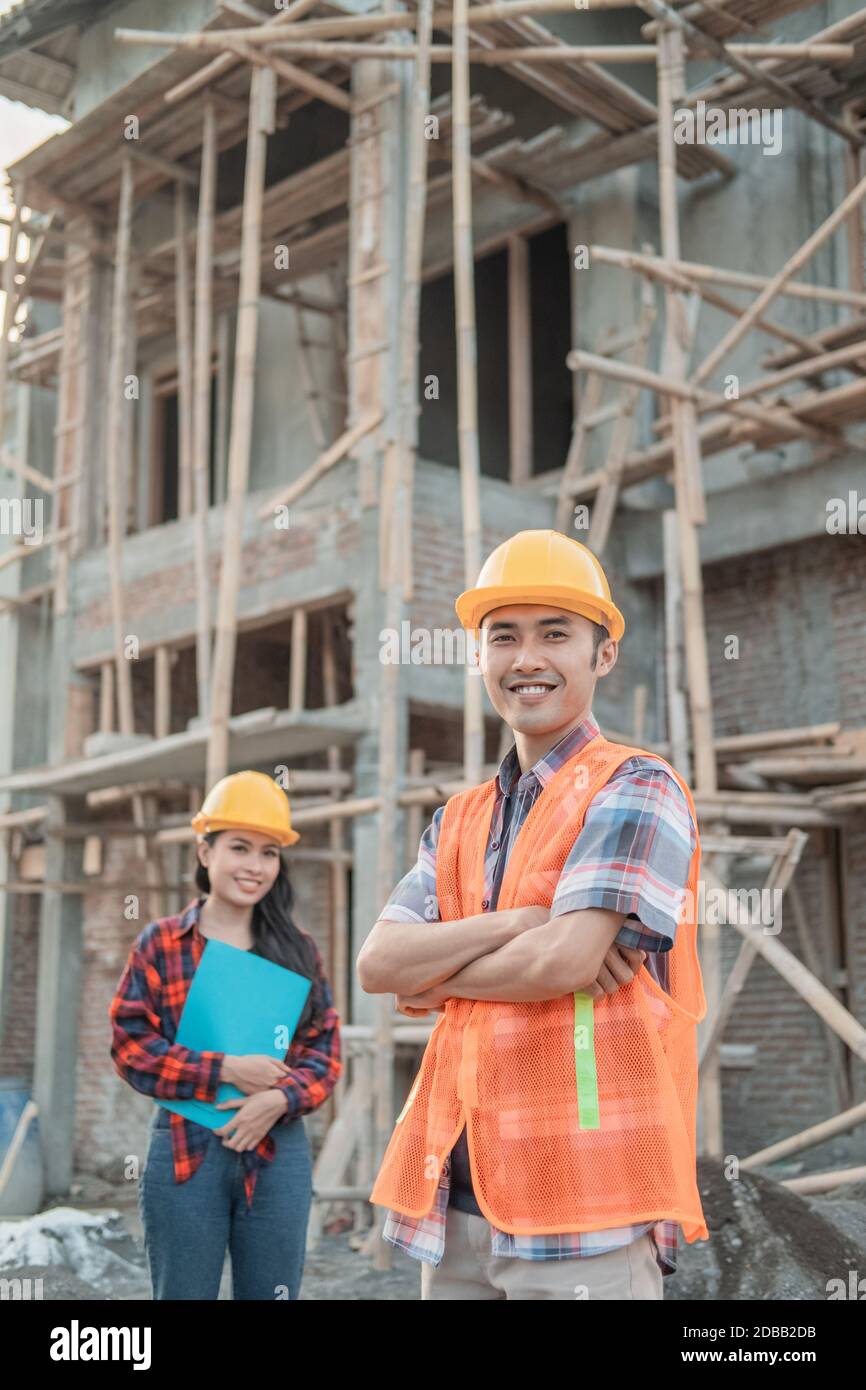 The male contractor stands with his crossed hands smiling at the camera ...