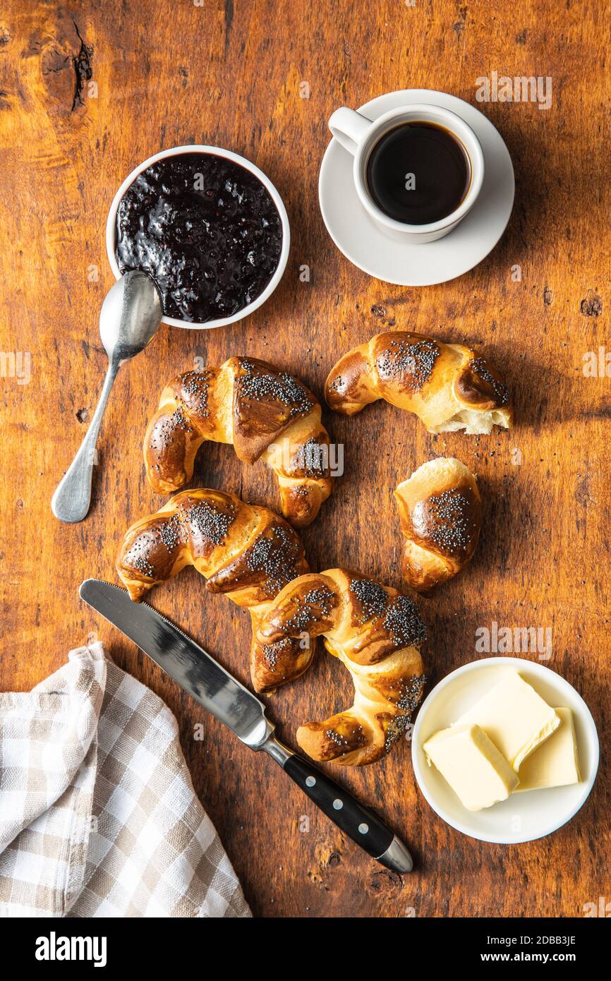 Sweet homemade croissants with poppy, jam, butter and coffee on wooden ...