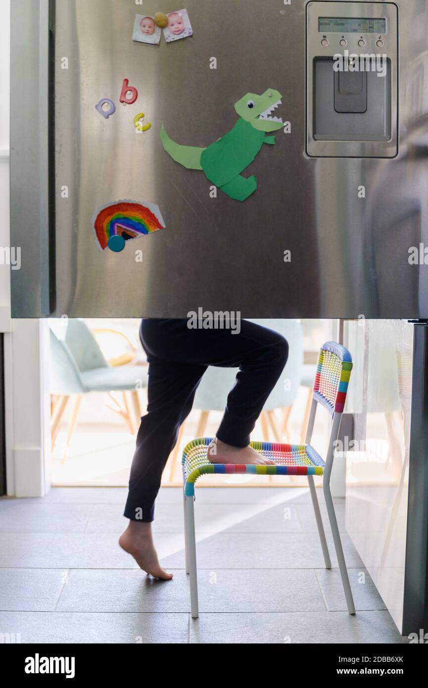 Boy (4-5) using chair while searching for food in fridge Stock Photo ...