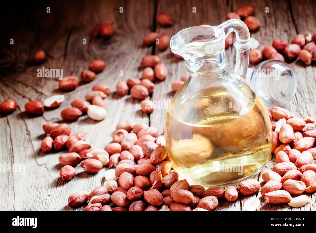 Peanut oil in a glass jar, raw peanuts, vintage wooden background ...
