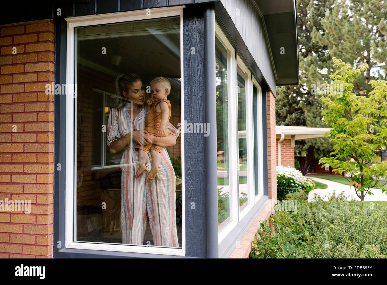 Mother with baby son (18-23 months) standing behind window Stock Photo ...