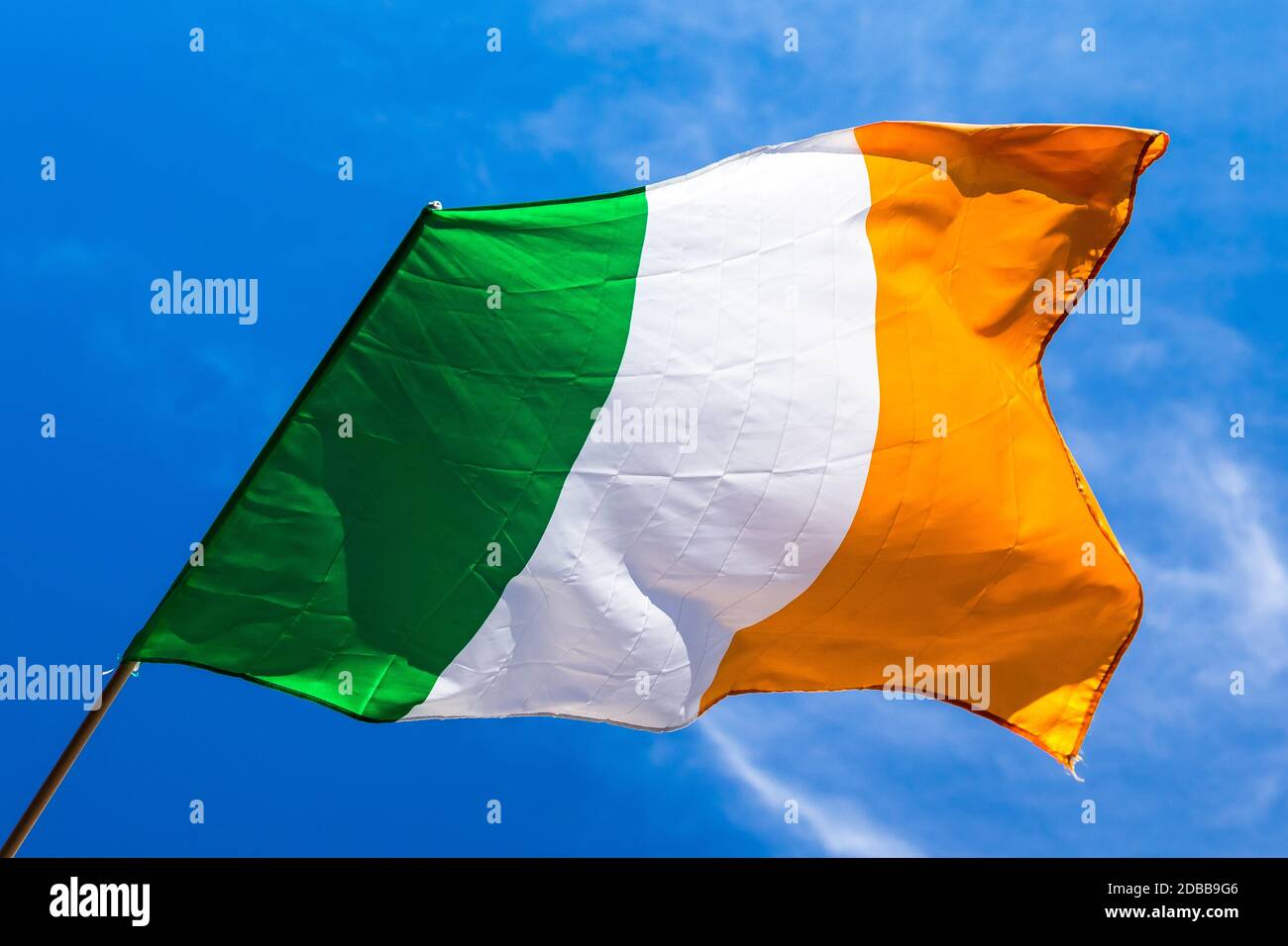 Irish flag fluttering in a brisk breeze against a bright blue sky ...