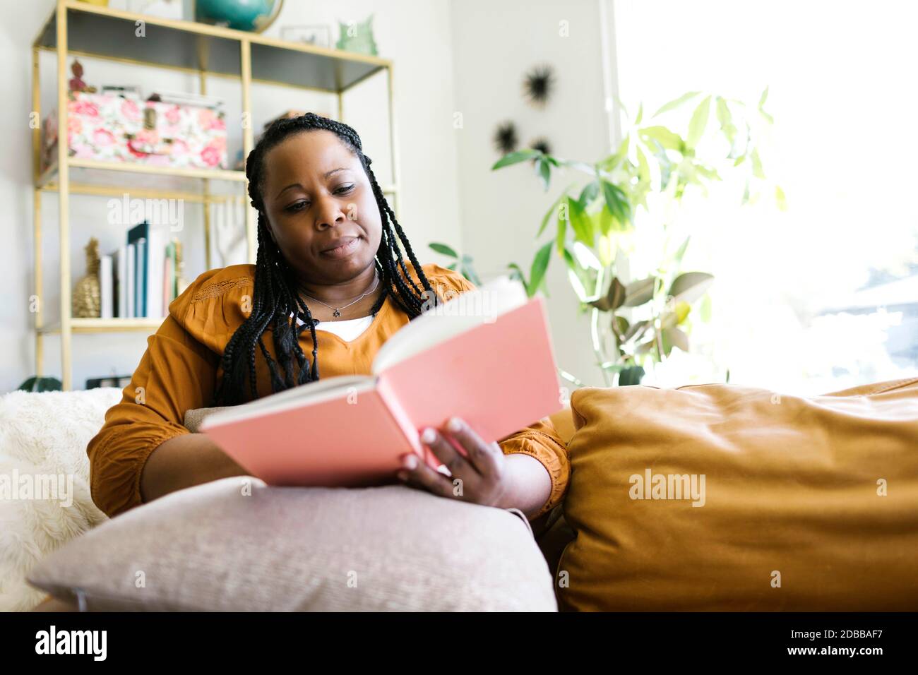 Black woman on sofa reading book hi-res stock photography and images ...