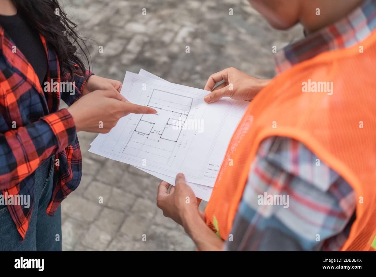 close up of male and female Asian contractors holding the building site ...