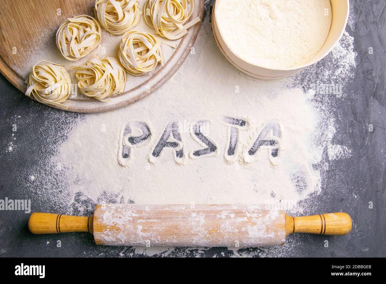 Homemade uncooked pasta tagliatelle and rocking for the dough on black ...