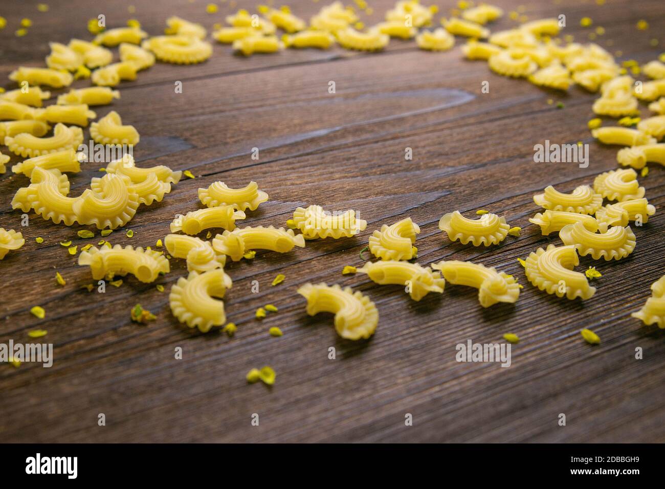 Pene Lisce pasta in the form of a circle on dark wooden background ...