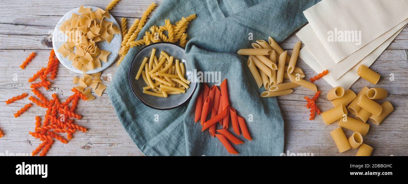 colourful mix of different noodles on wooden background photographed ...