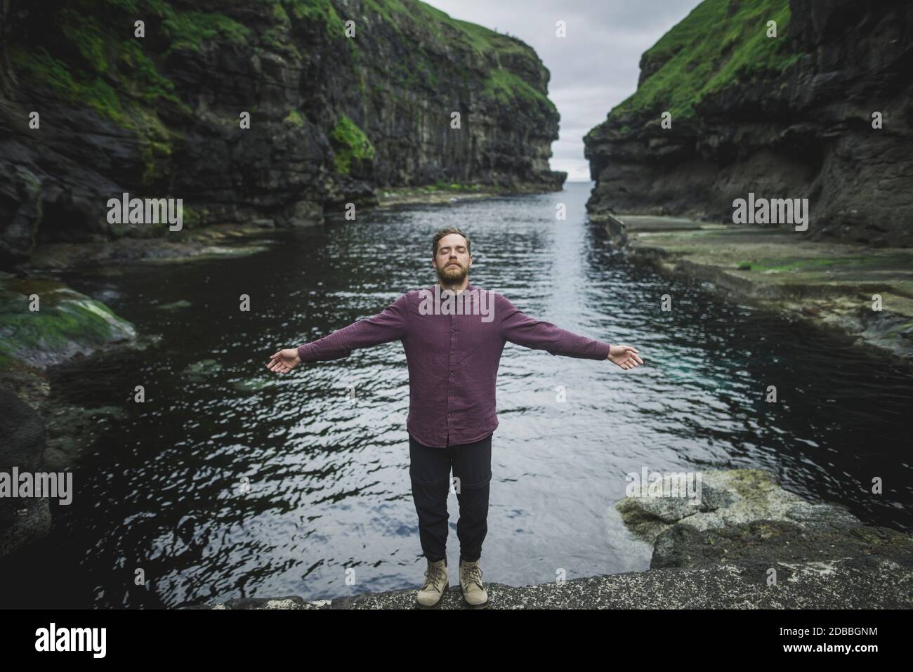 Denmark, Faroe Islands, Gjgv, Man standing inn gorge with outstretched ...