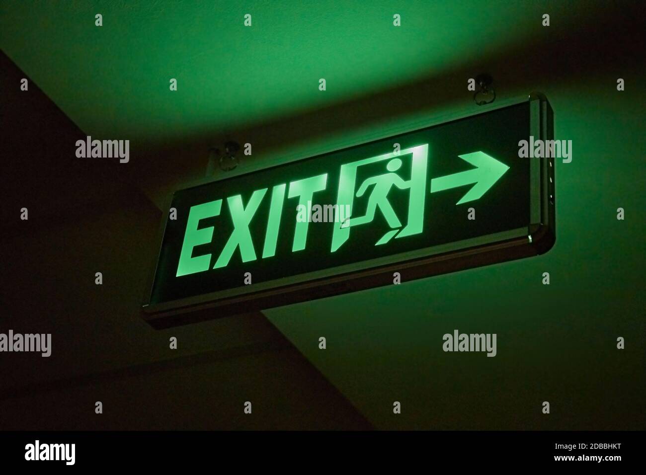 Emergency exit sign glowing in the dark corridor Stock Photo - Alamy