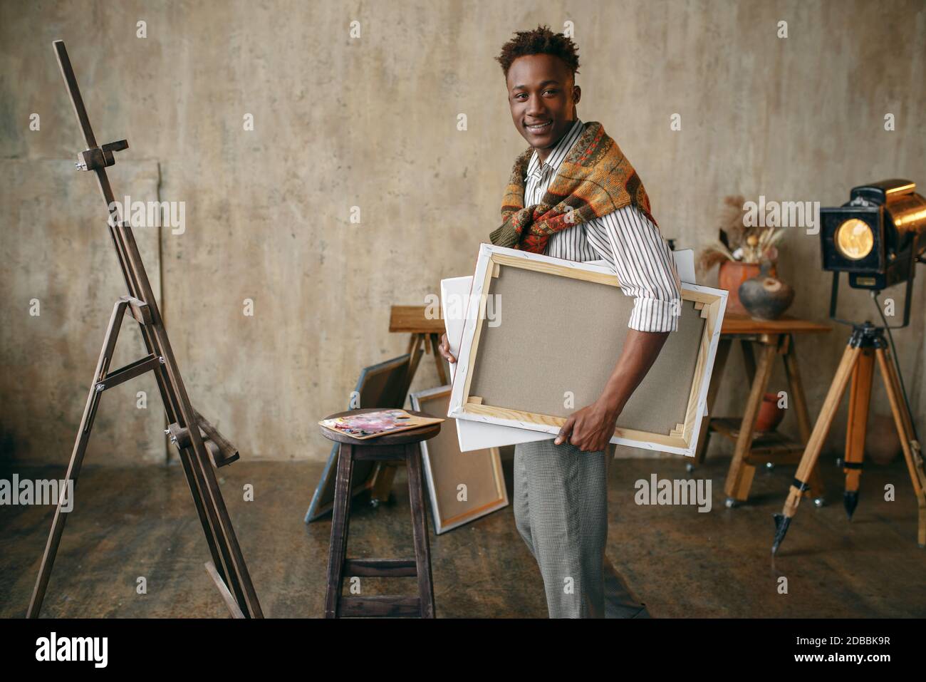 Smiling painter with canvas standing in art studio. Male artist draws ...