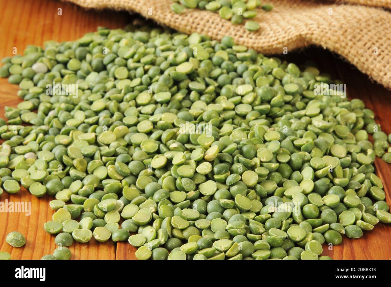 A burlap bag of organic dried split peas on a rustic wooden counter ...