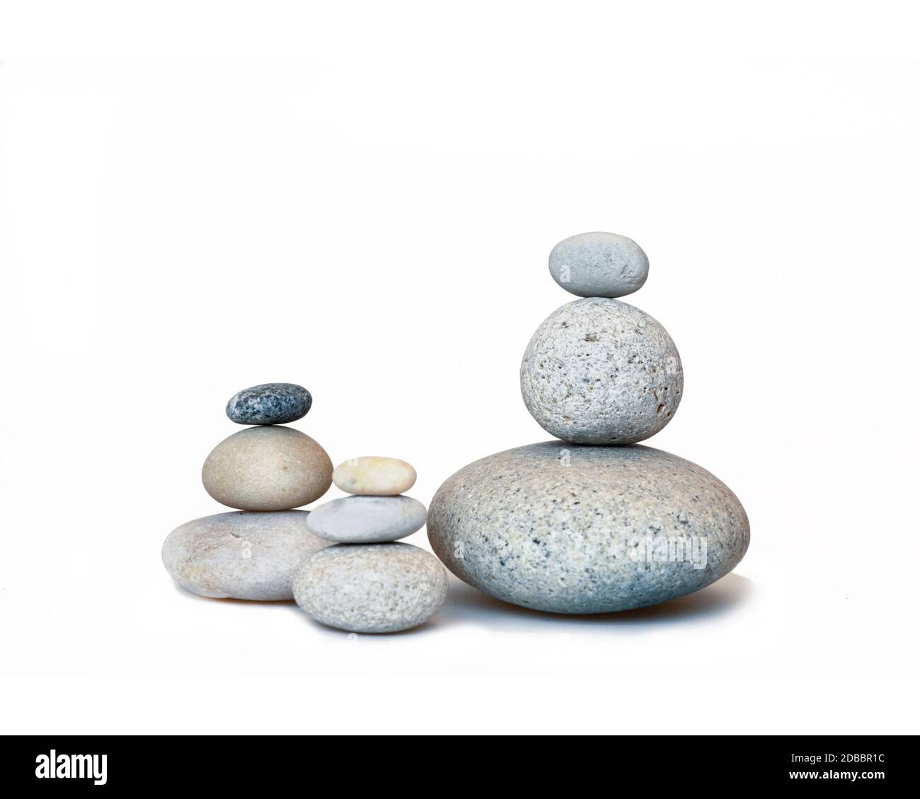 group of three balanced pebble stone cairns across a white background ...