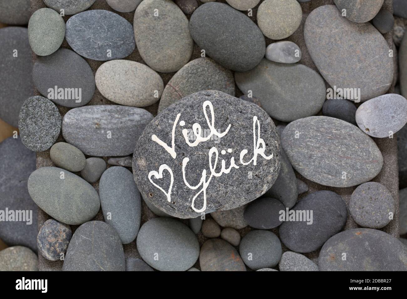 smooth grey pebble with white handwritten german text for good luck ...