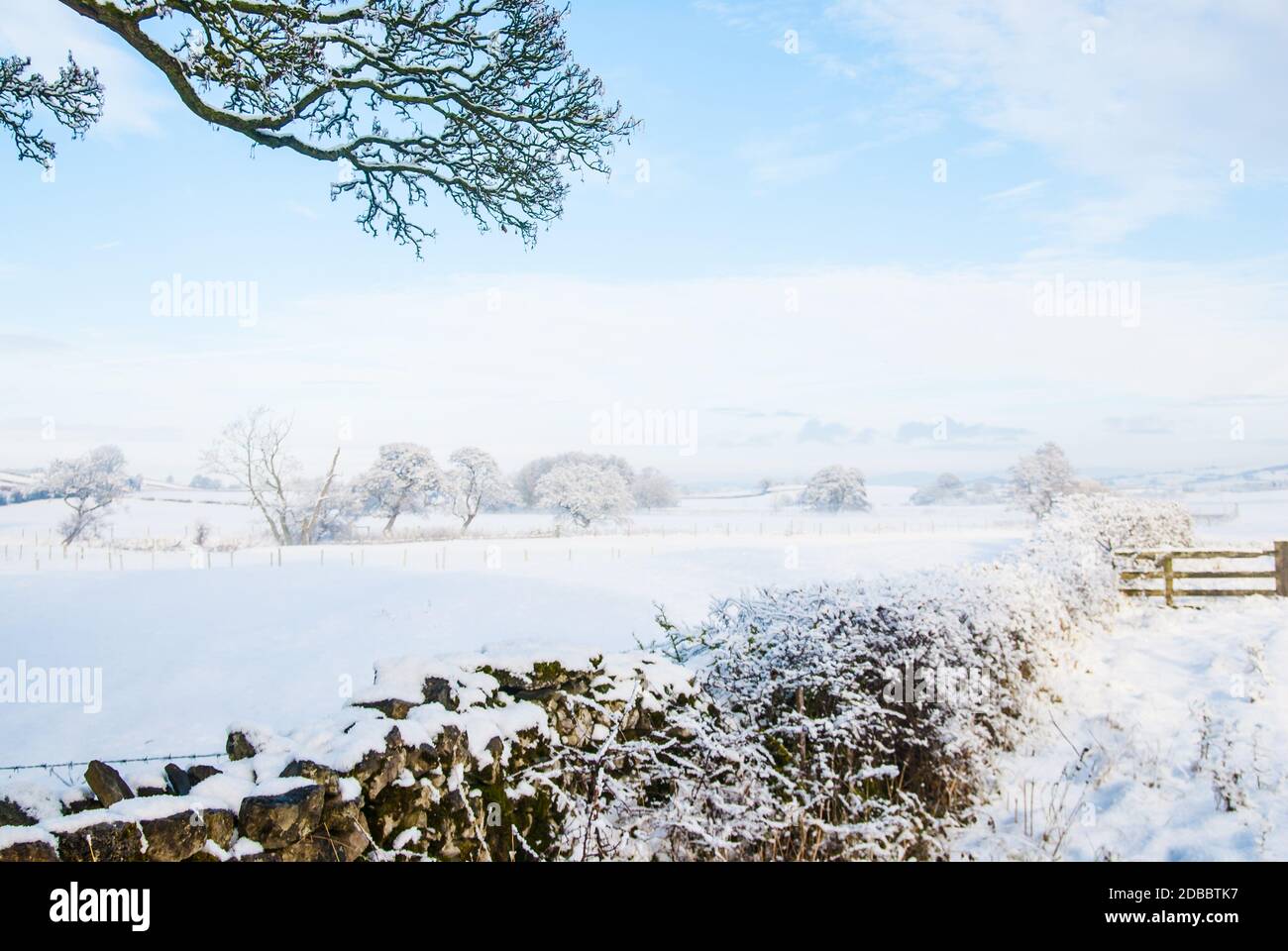 a dry stone wall and snow covered field with wooden fence in the ...