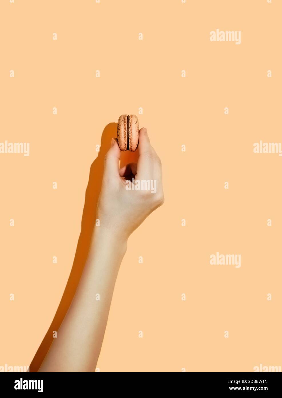 hand holding french macaroon or macaron isolated on yellow pastel ...