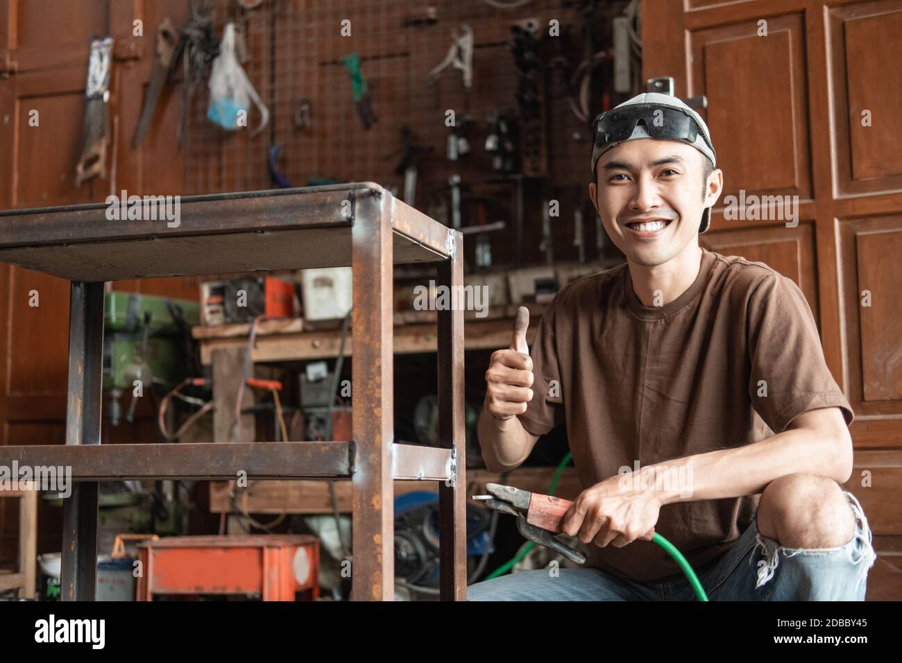 close up of Male welder smiling with a thumbs up while holding an ...