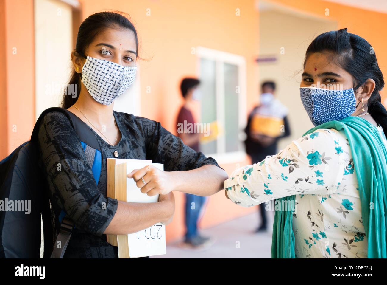 Concept of college reopen, two girls in medical mask greeting with ...
