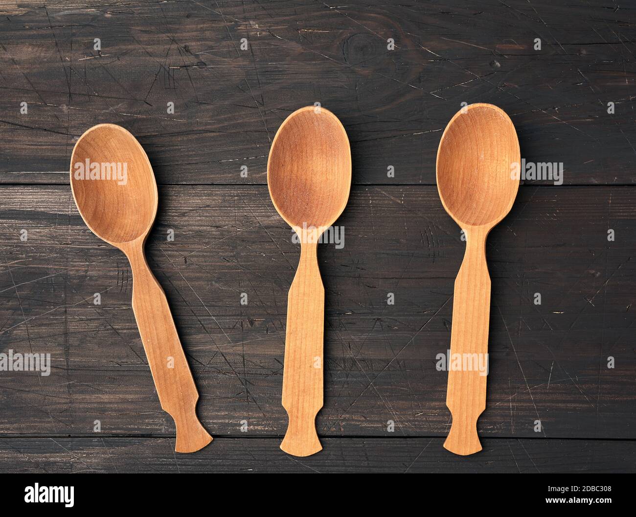three empty wooden spoons on a brown wooden background from boards, top ...