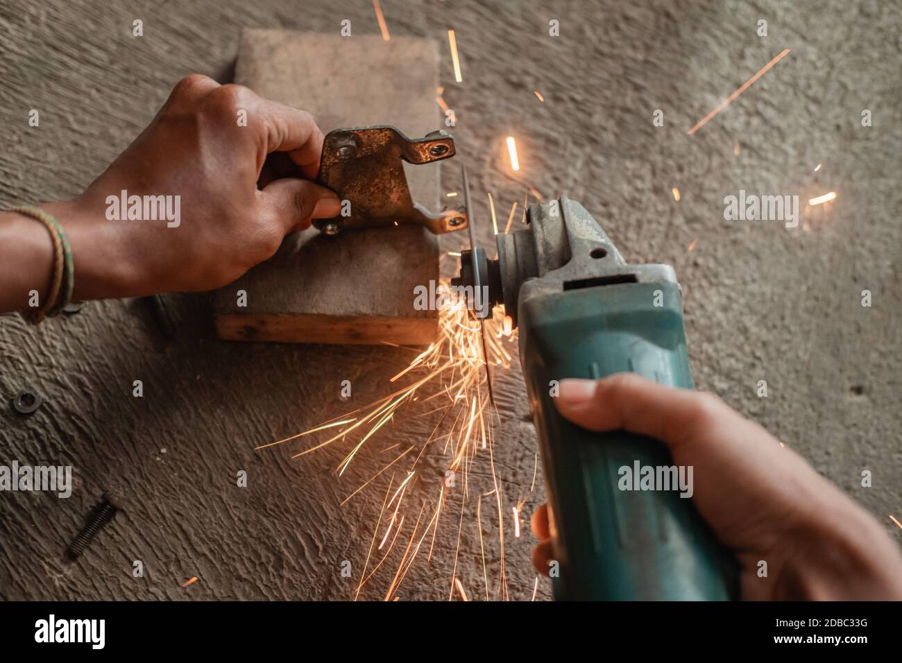 close up of welder's hand using a grinder to smooth the surface of the ...