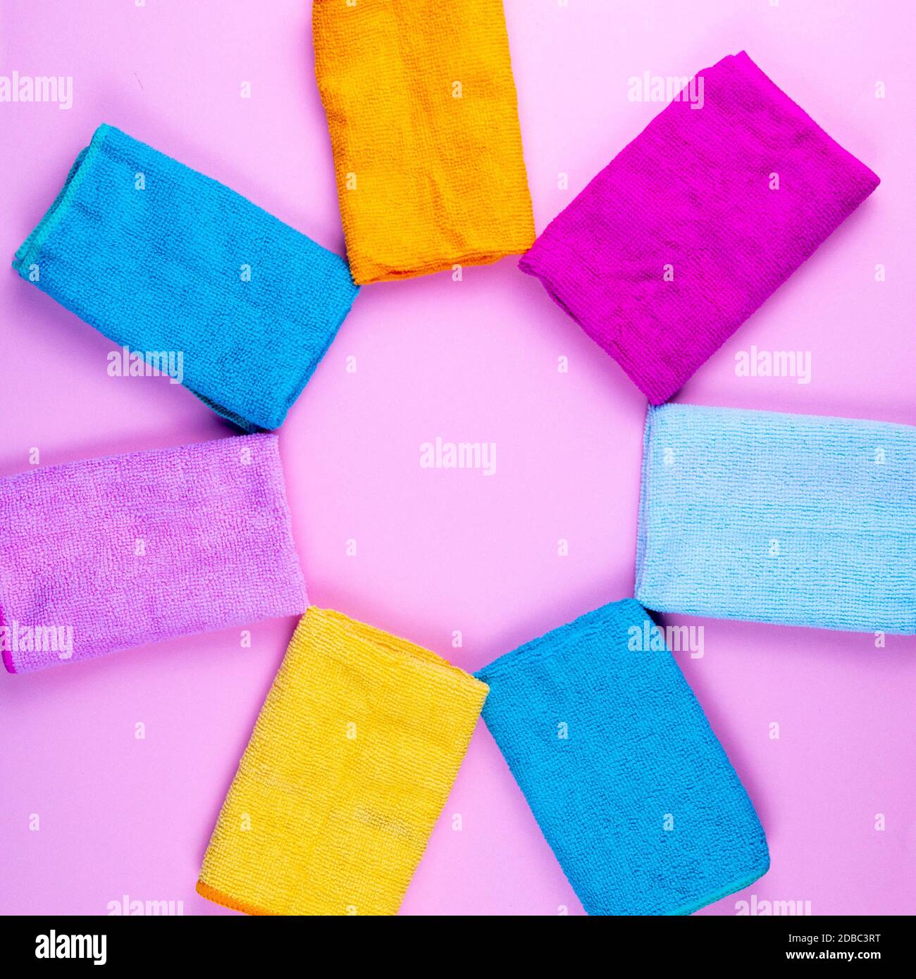 Multi-colored towels laid out in the form of the sun on a pink ...