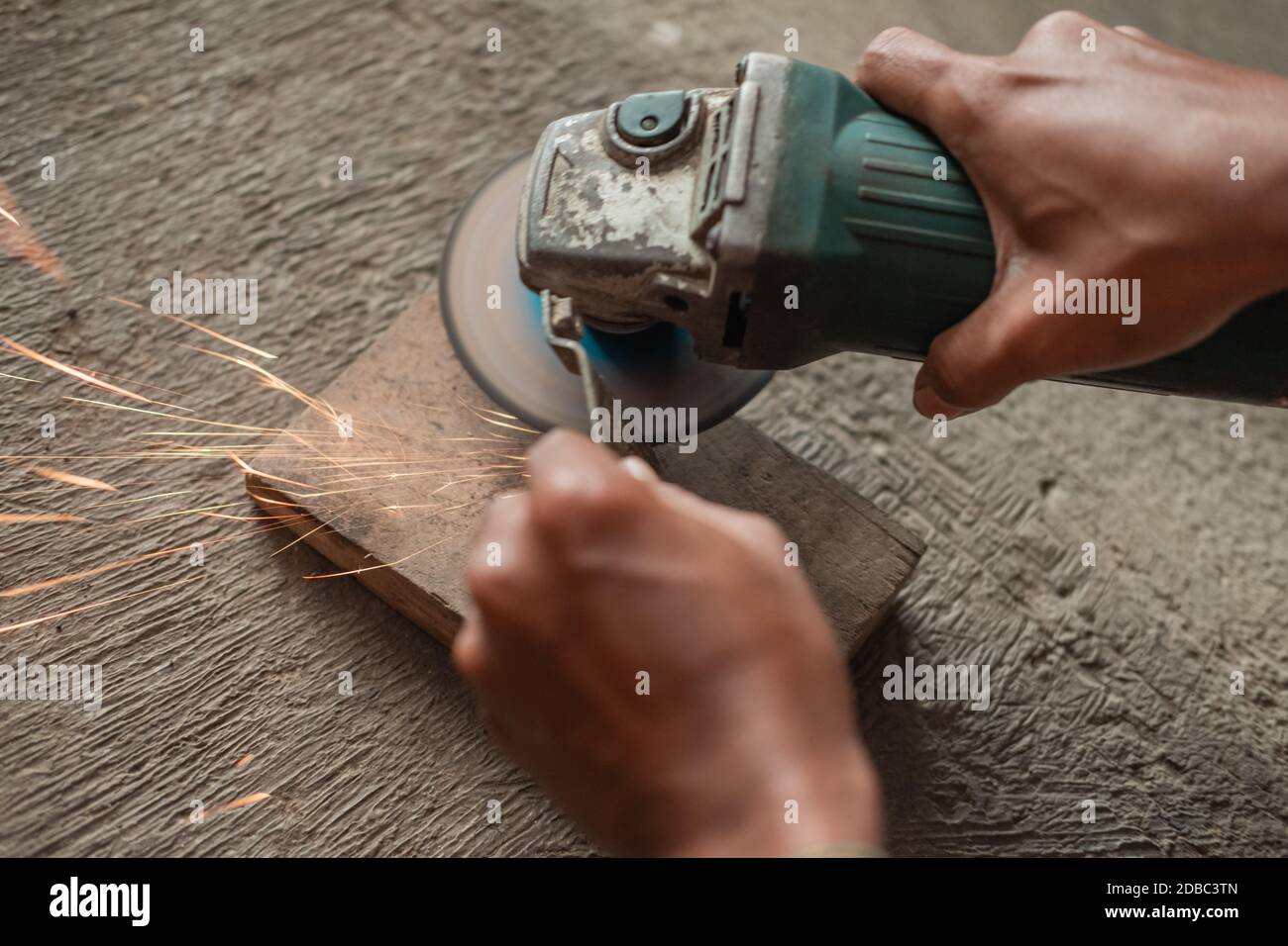 close up of welder's hand using a grinder to cut iron with a wooden ...