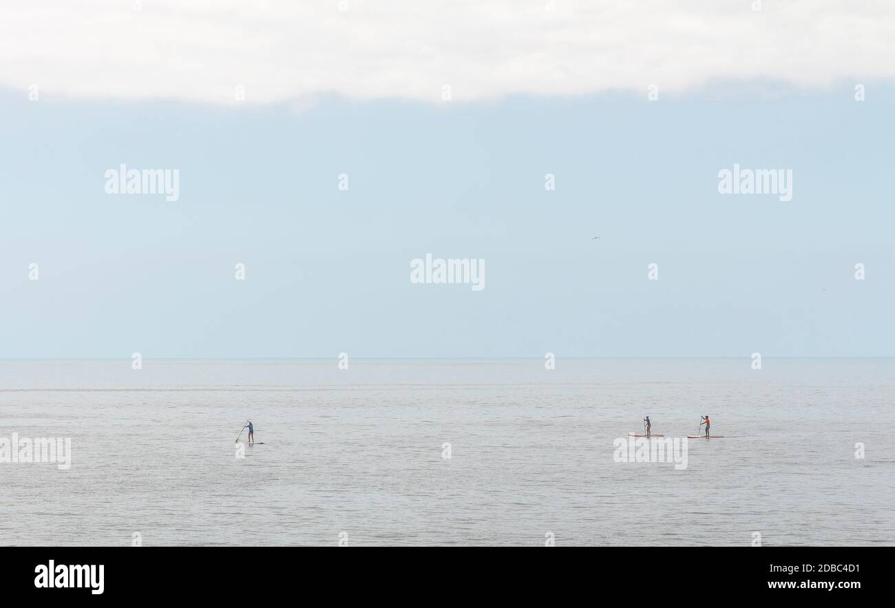 Three people practice paddle surfing in a totally calm sea Stock Photo ...