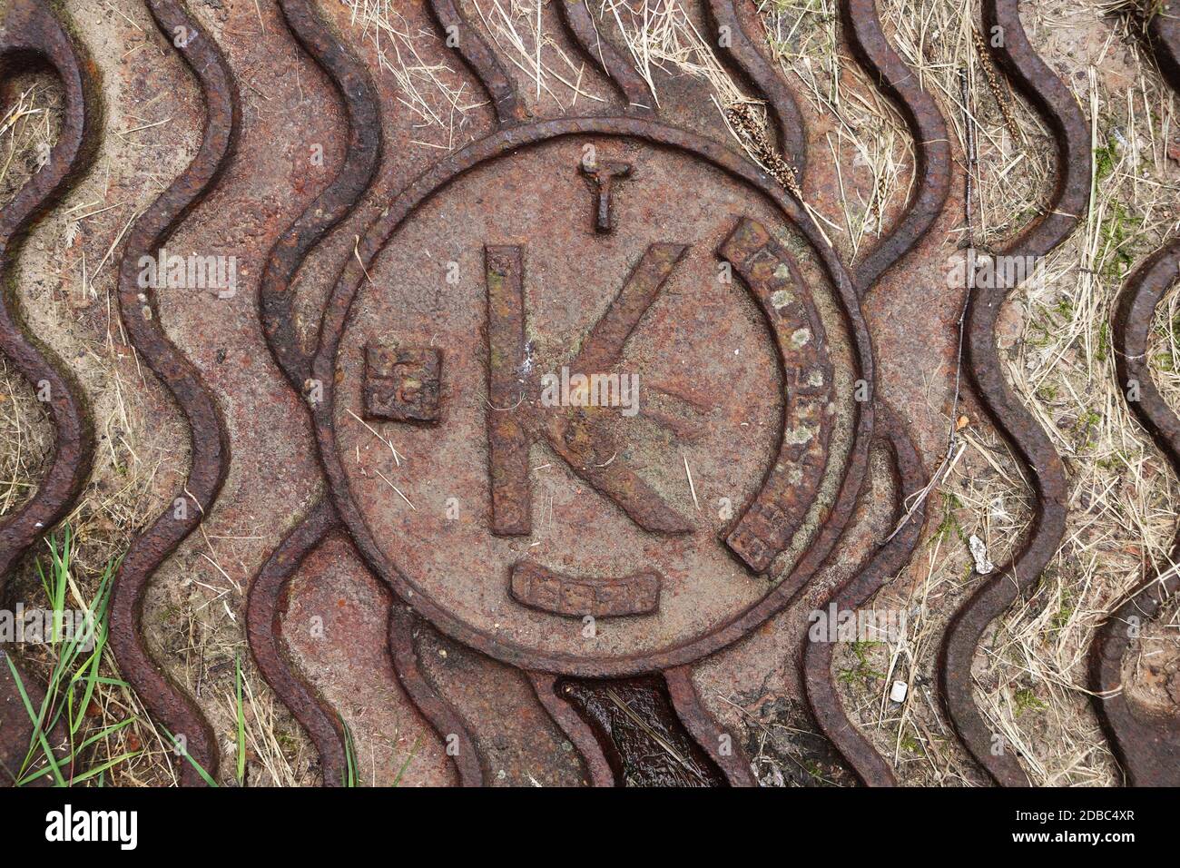 Rust metal hatchwaywith big K letter and wave ornament. Urban city ...