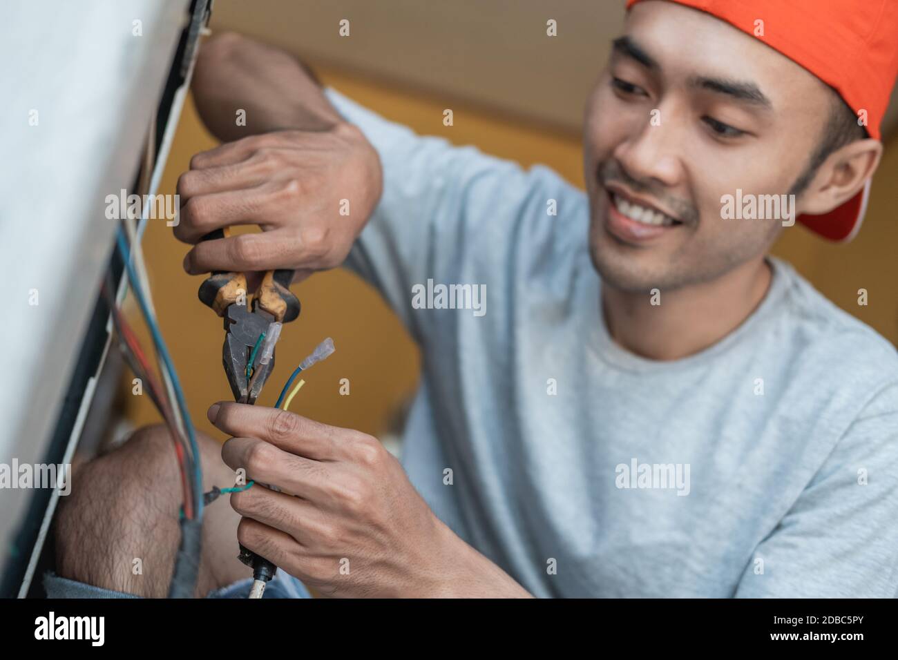 close up of an asian electronics worker using pliers to fix a washing ...