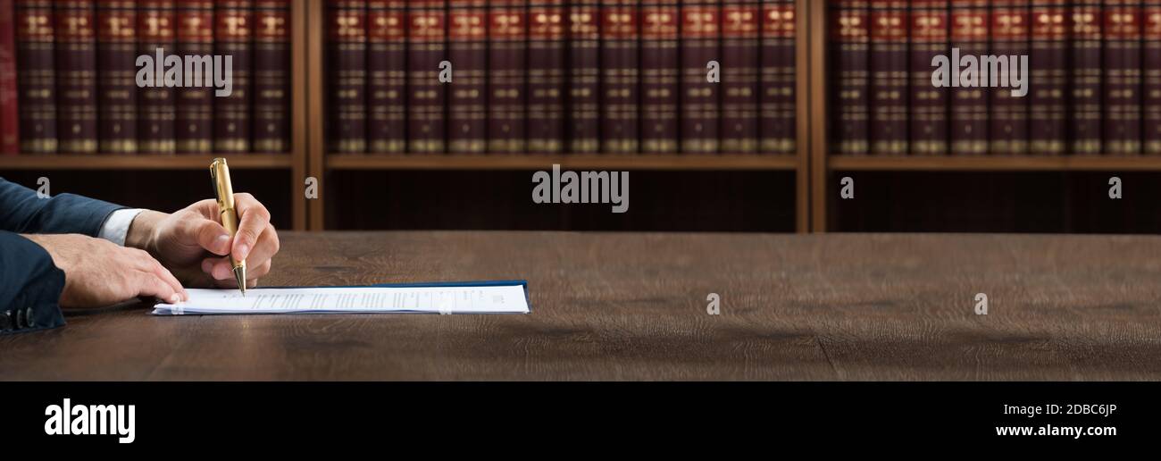 Lawyer Doing Legal Document Scrutiny At Desk With Books At Background ...