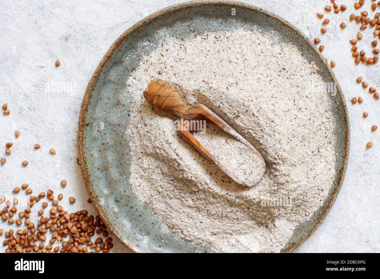 Buckwheat flour in a plate with a spoon and buckwheat grain top view ...
