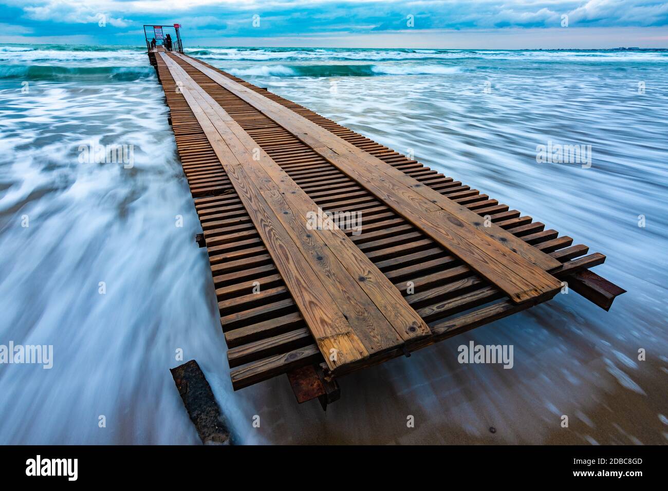 Pier going to sea and sea surf after sunset Stock Photo - Alamy