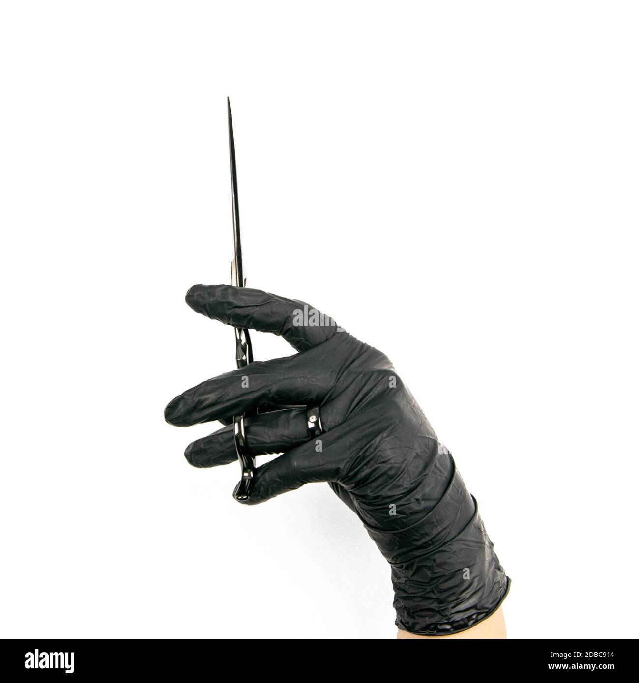 Gloved hand holding a black scisors on an isolated white background ...