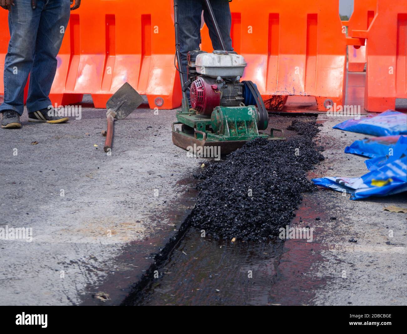 Worker use vibratory plate compactor compacting asphalt at road repair ...