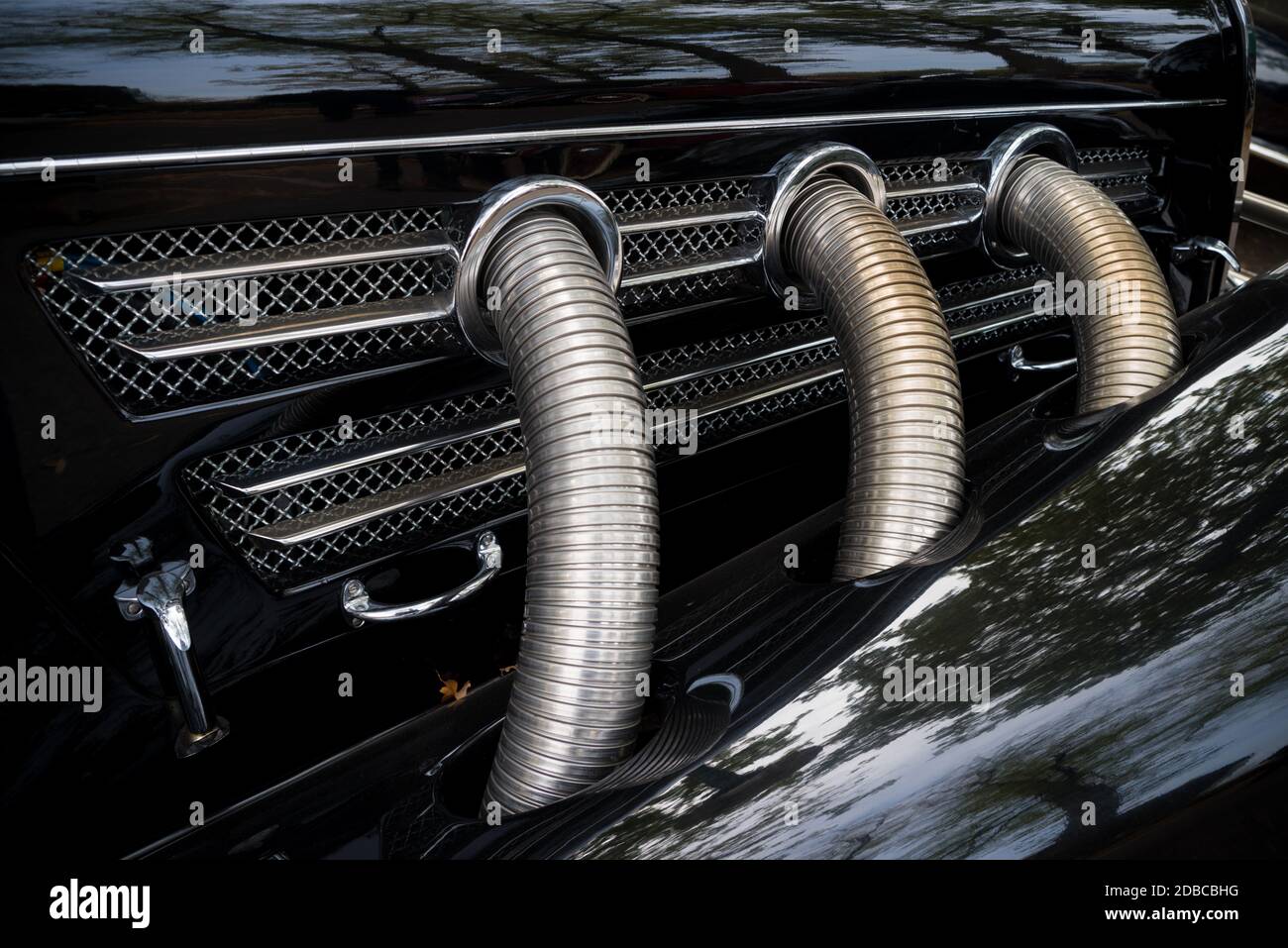 three chrome exhaust pipes on a black oldtimer car Stock Photo - Alamy