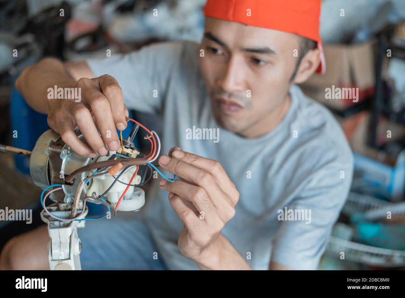 electronics repairman fixes a broken wire in a broken fan at an ...