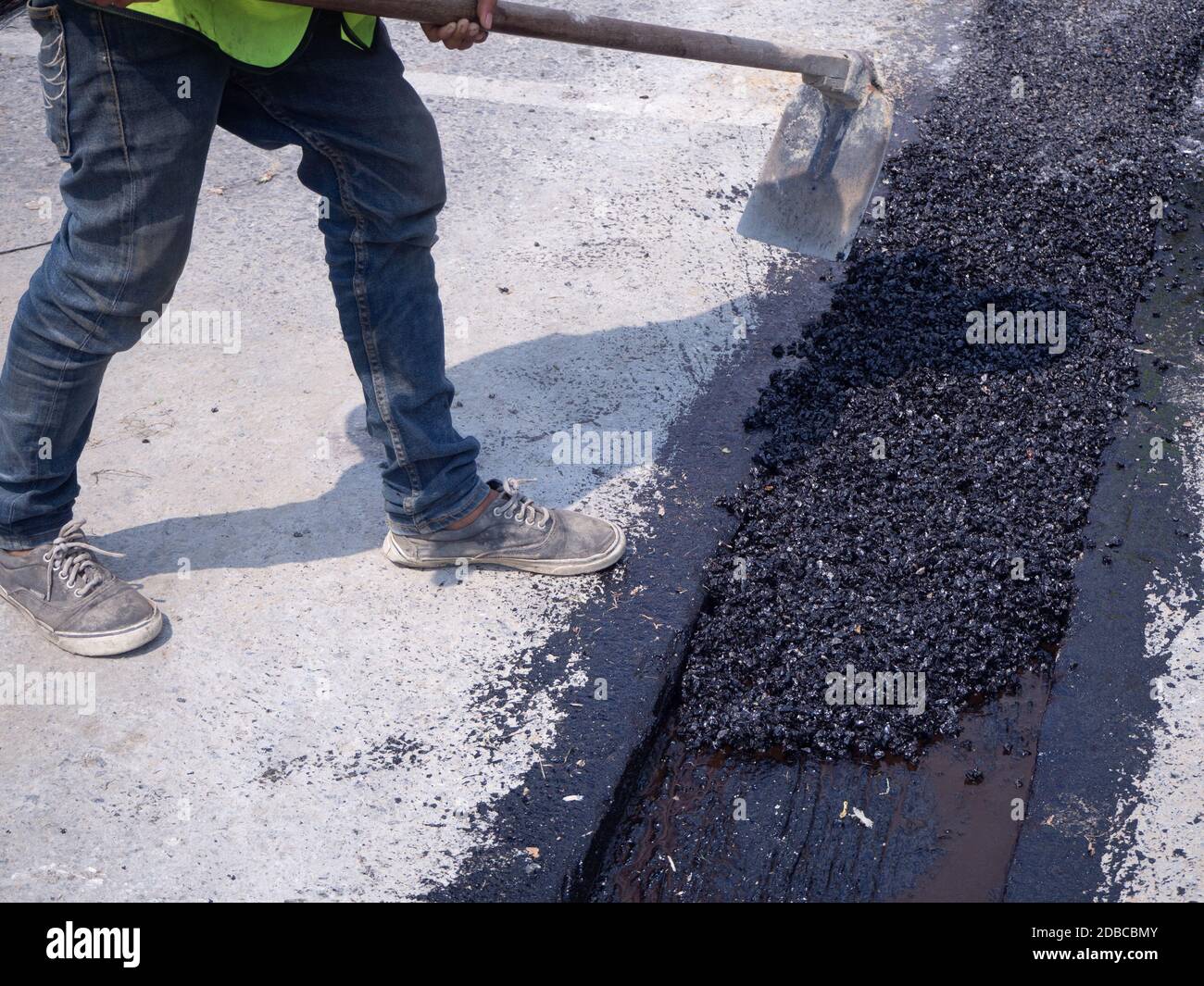 Worker use vibratory plate compactor compacting asphalt at road repair ...