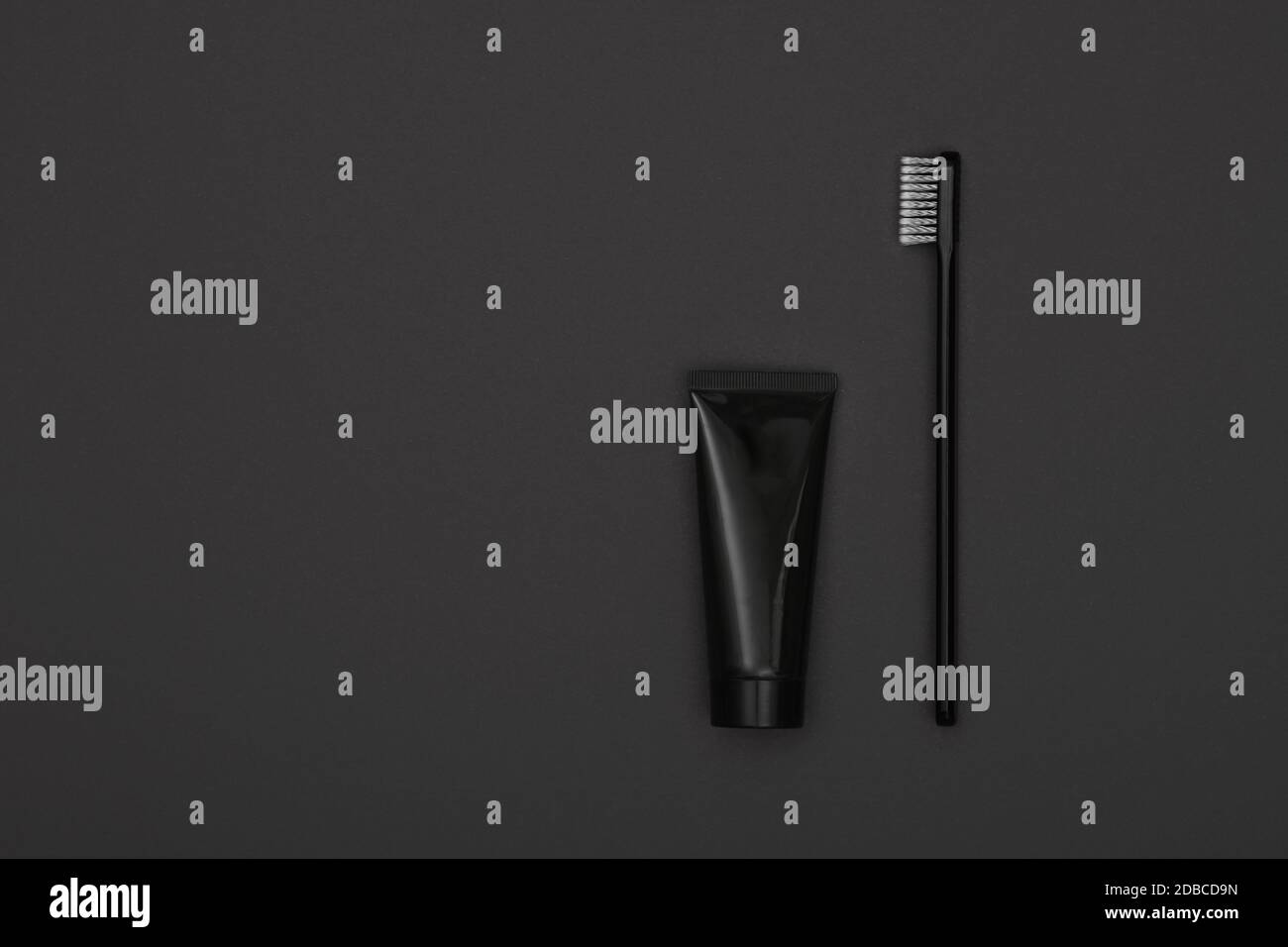 Close up one black toothpaste tube and toothbrush over dark grey ...