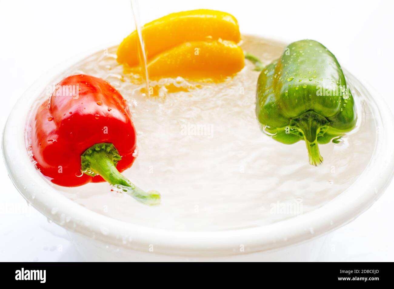 Bell pepper soaked in water. Washing fresh vegetables on white ...