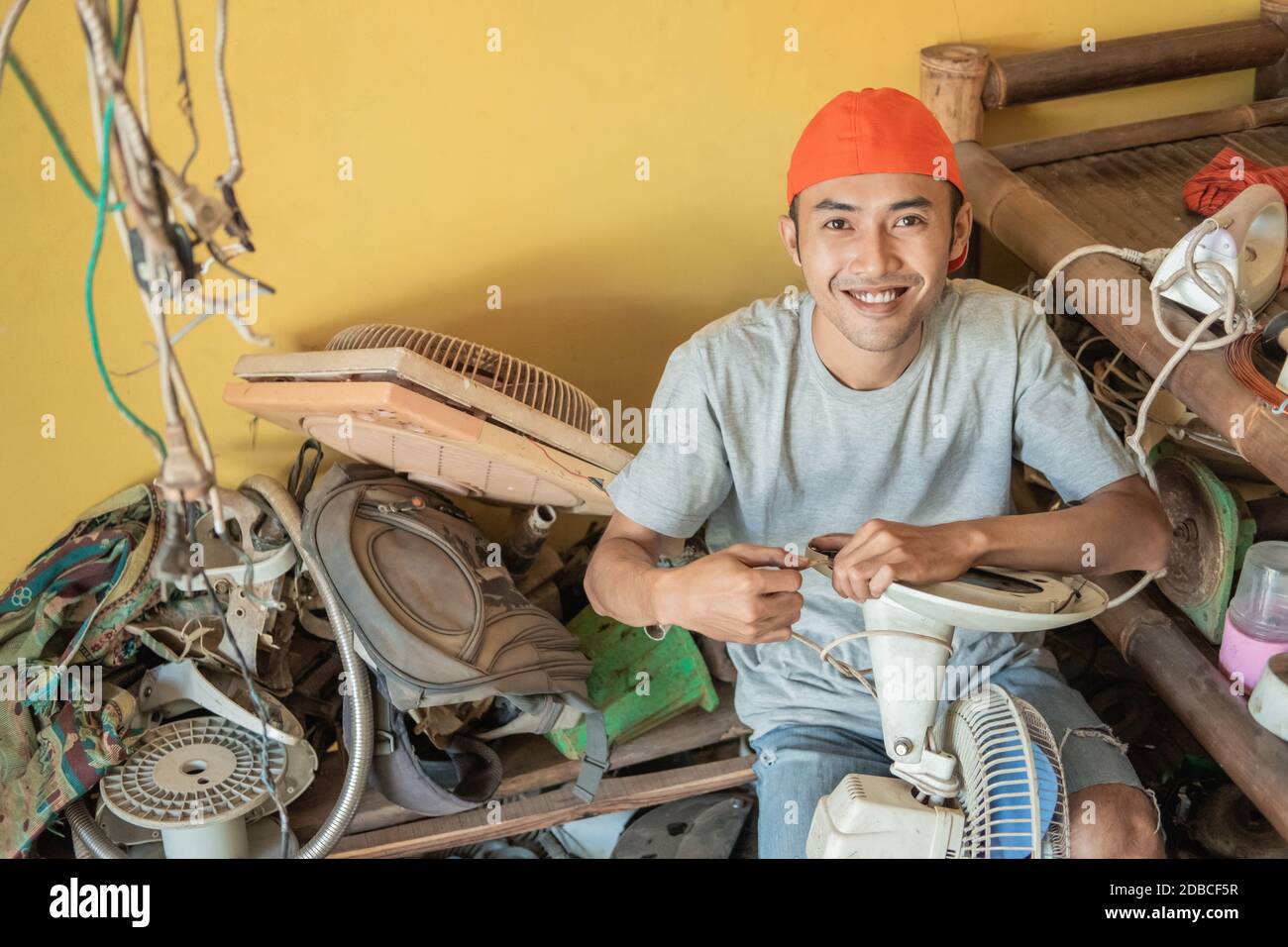 electronics repairman smiles at the camera while holding the fan cable ...