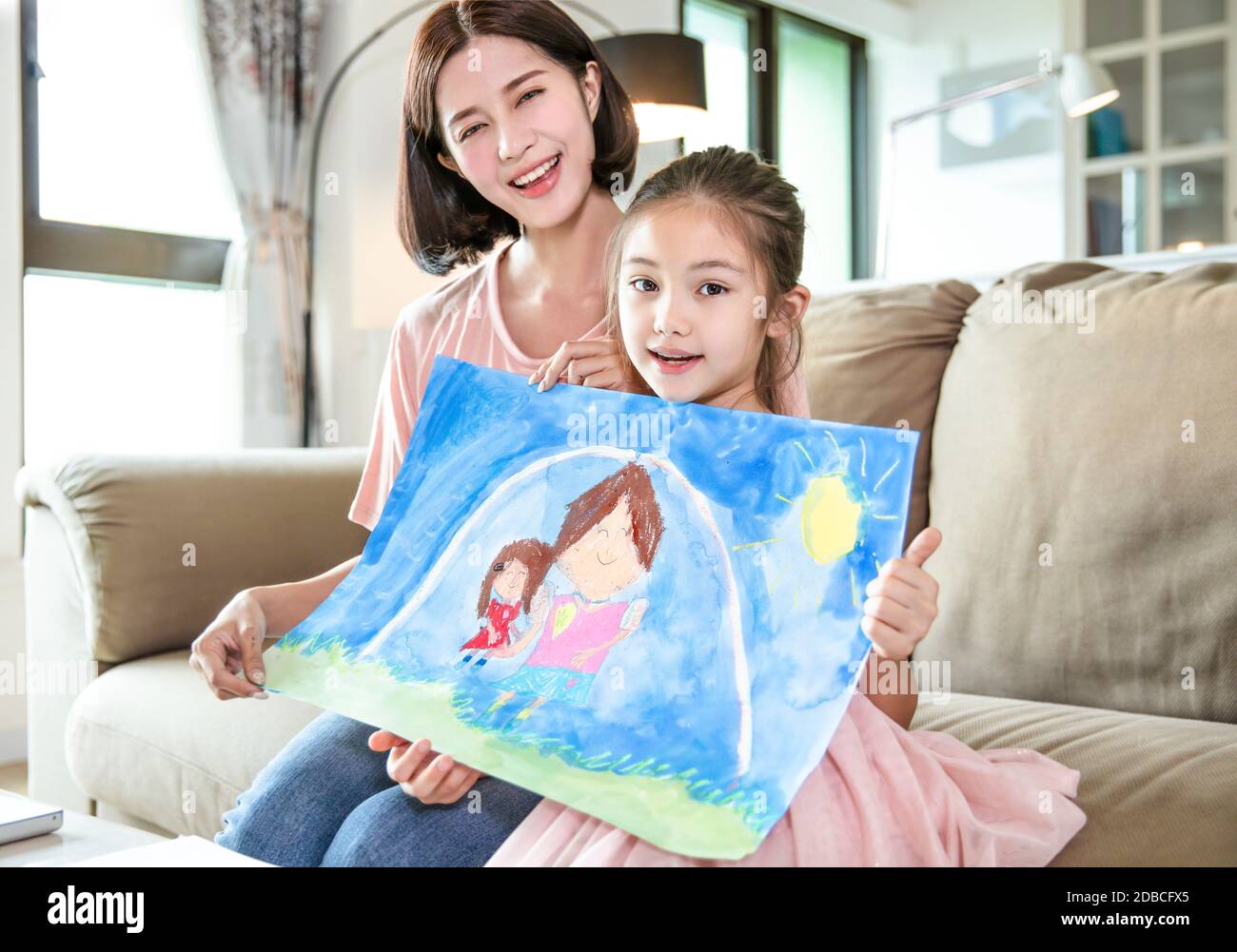 little girl showing Color pencil drawing family picture to her mother ...