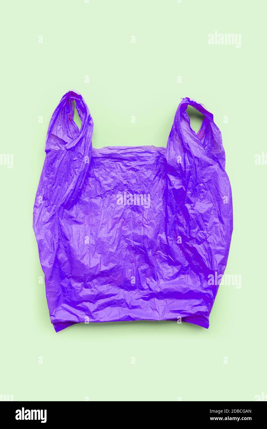 Purple plastic bag on green background. Environment pollution concept ...