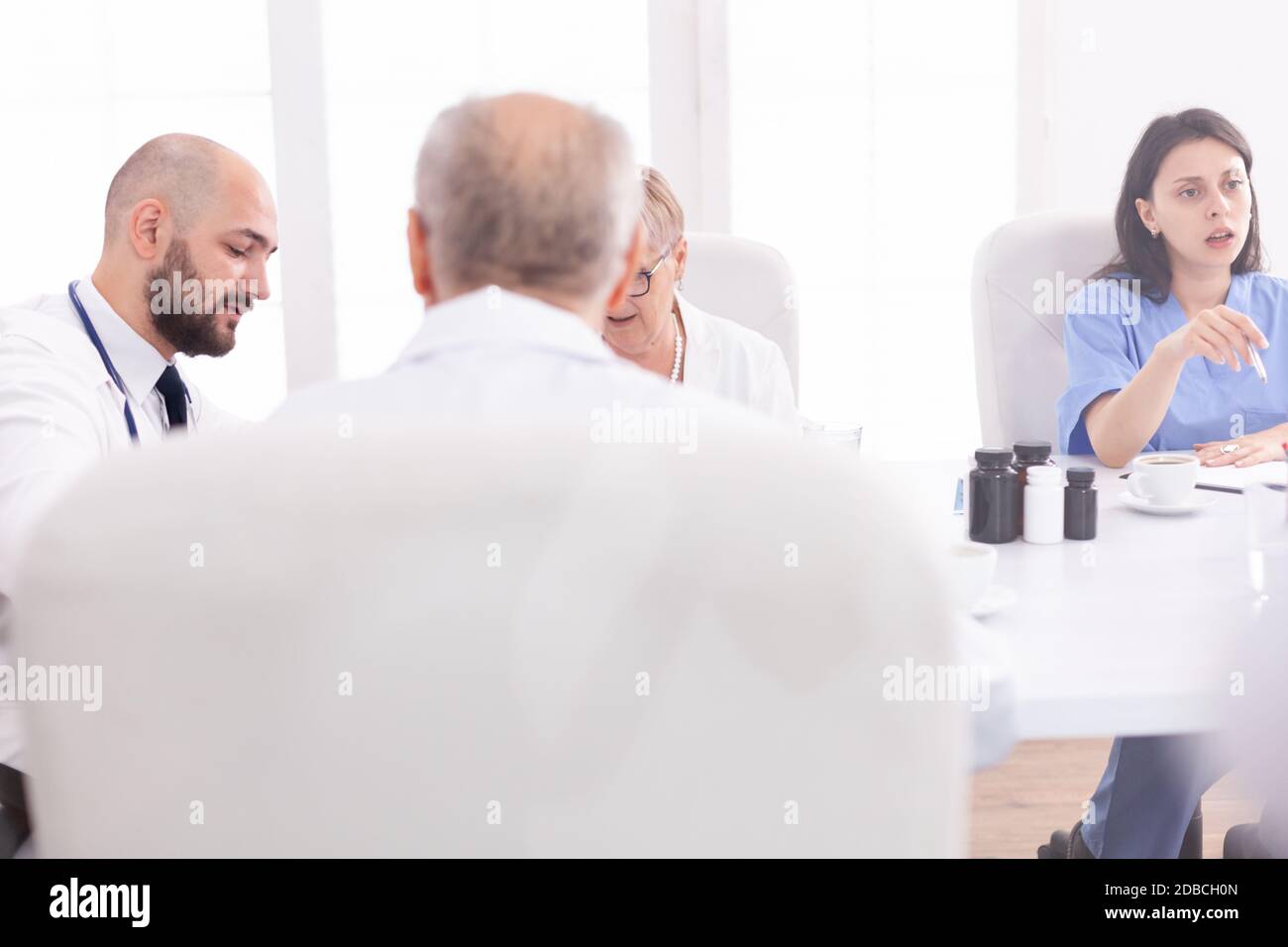 Young expert doctor talking with medical staff in conference room ...