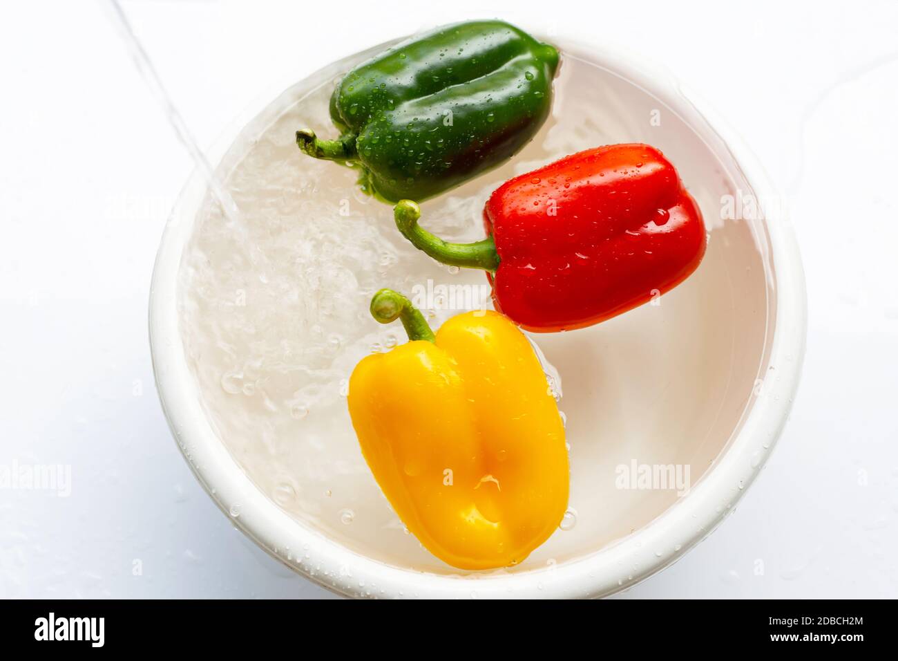 Bell pepper soaked in water. Washing fresh vegetables on white ...