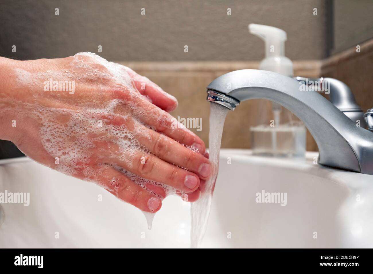 Washing hands with soap and water in bathroom sink, protection against ...