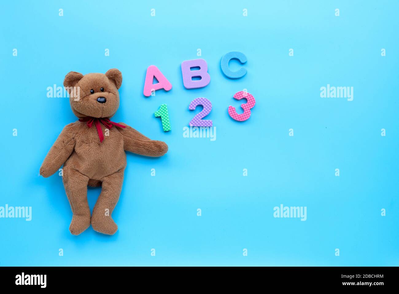 Brown bear toy with english alphabet and numerals on blue background ...