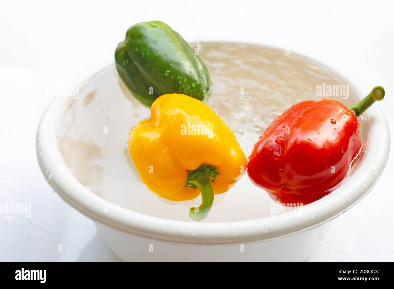 Bell pepper soaked in water. Washing fresh vegetables on white ...