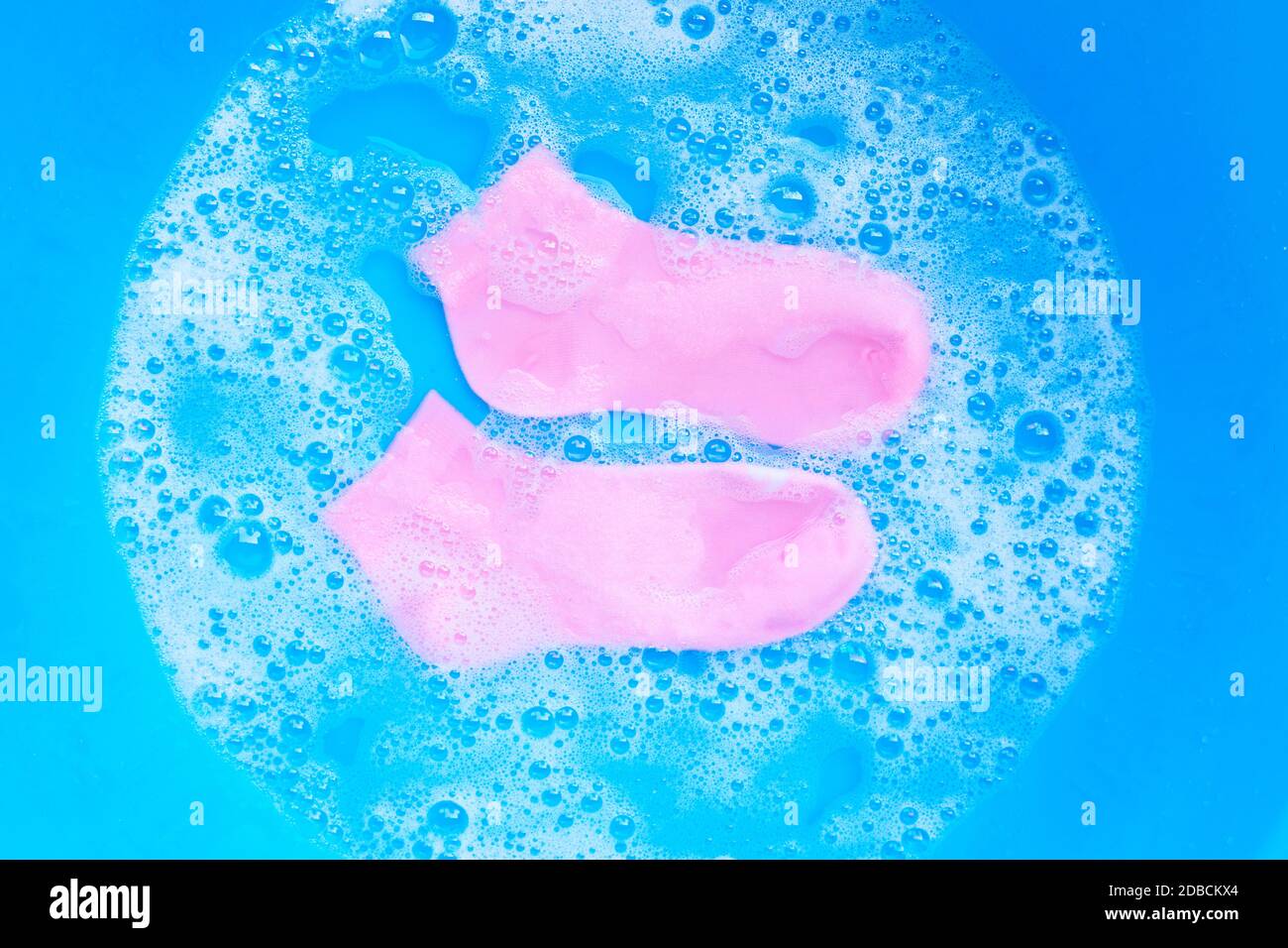 Pink socks soaking in powder detergent water dissolution. Laundry ...