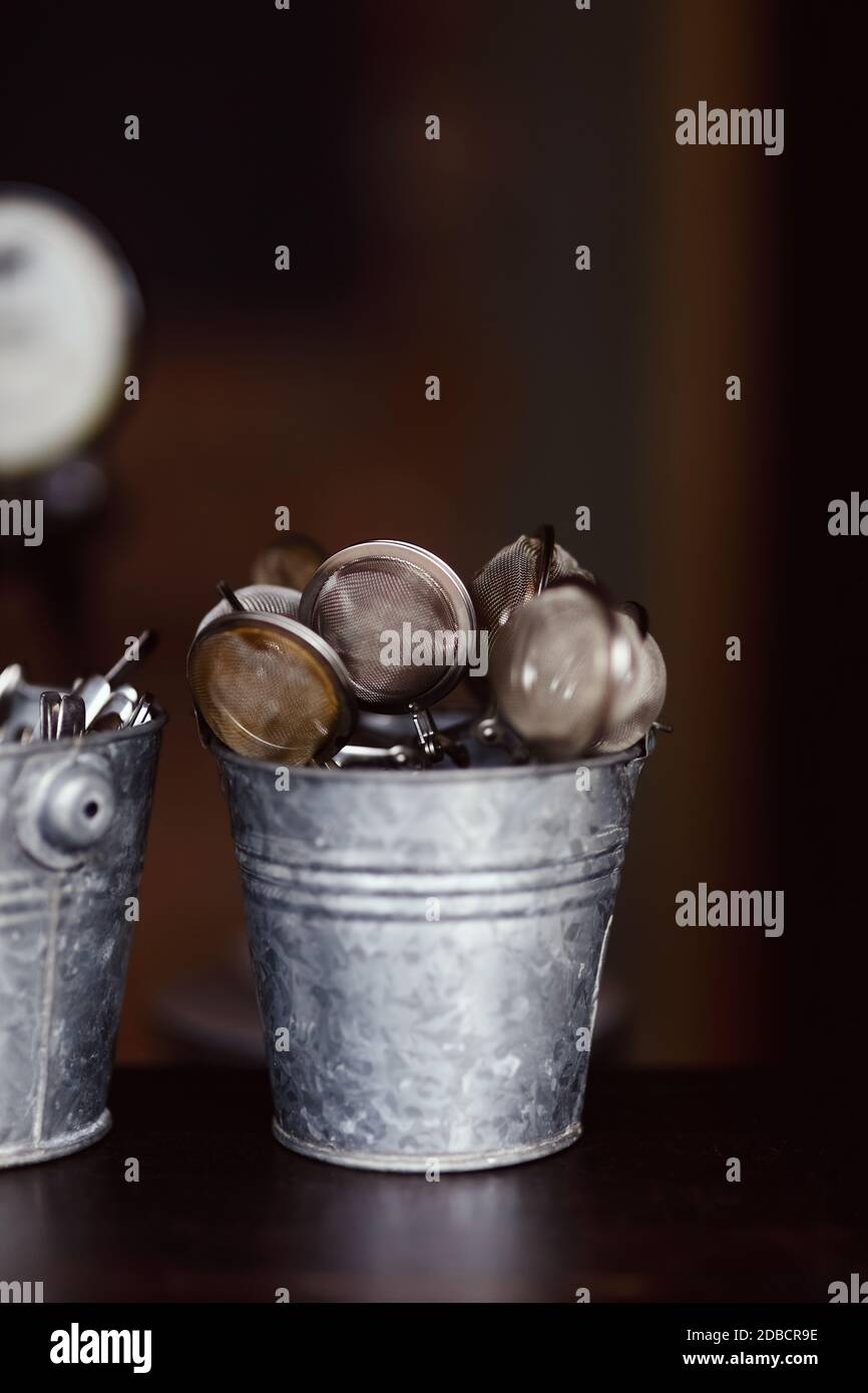 Tea strainers in a zinc bucket on a bar counter Stock Photo - Alamy
